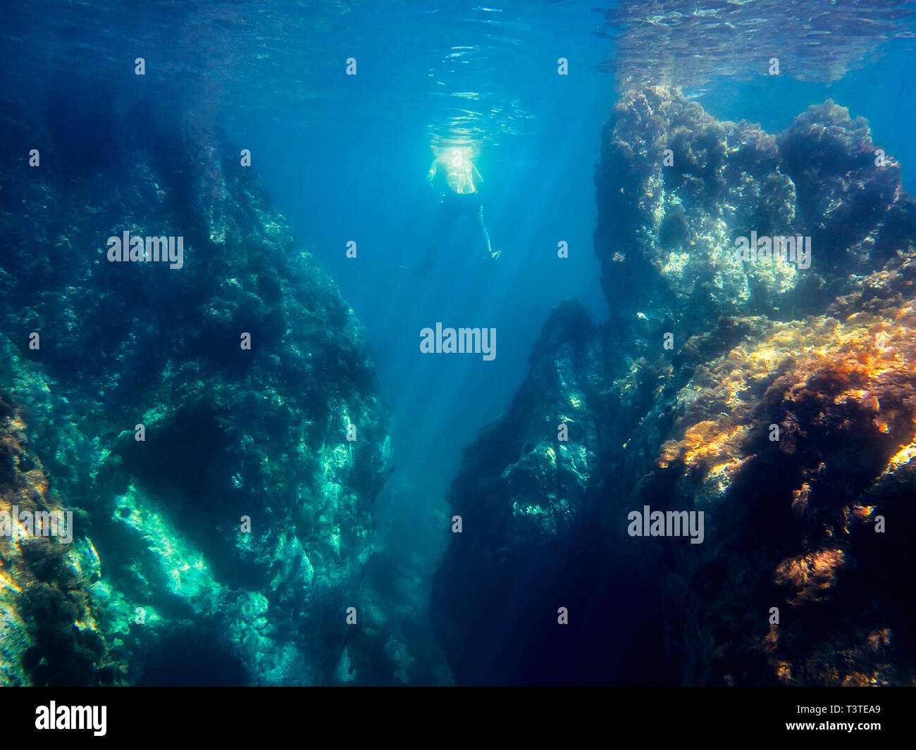 Man floats relaxed in the ocean between huge rocks that come from the ...