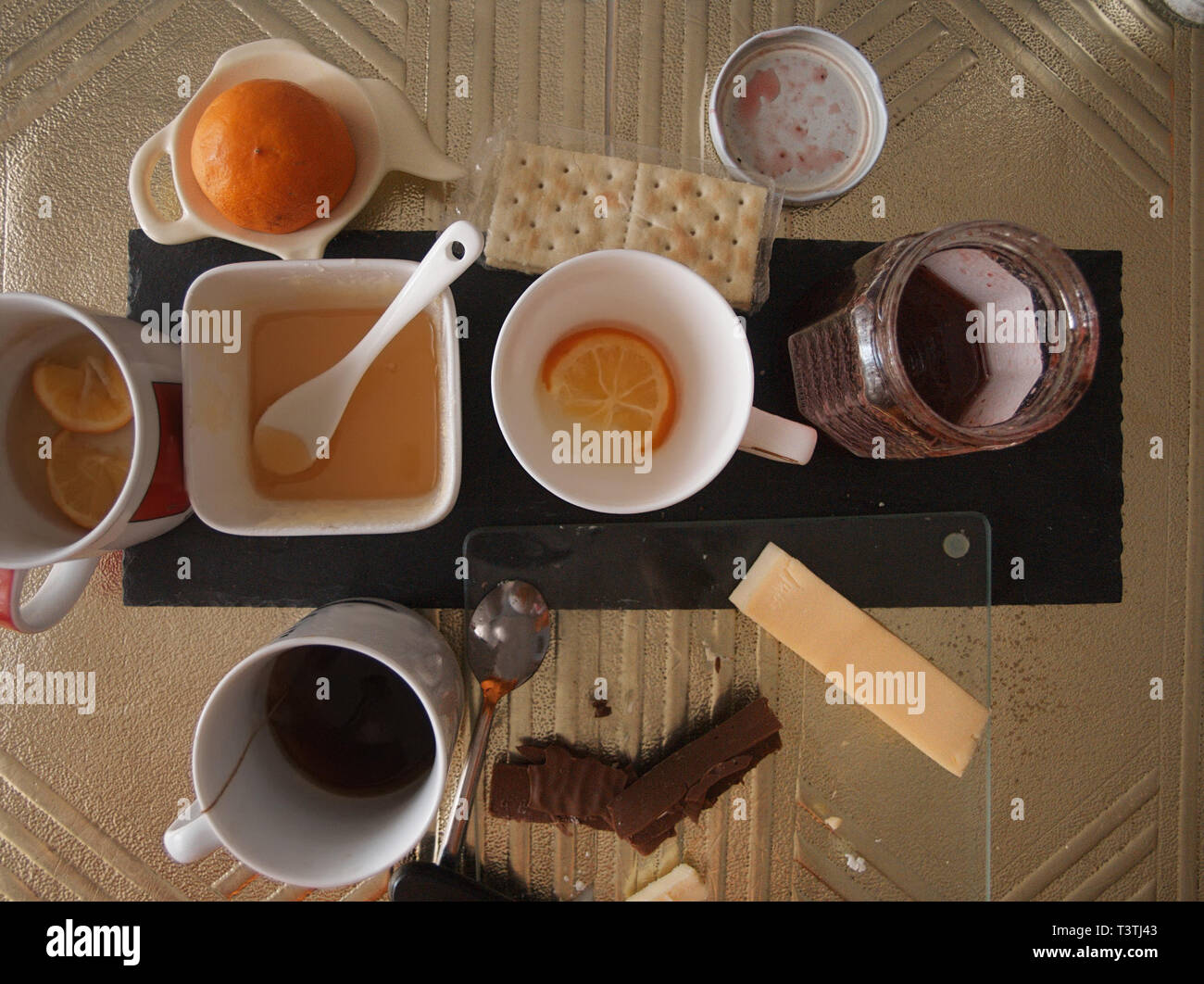 Tea cups and meal left in mess on a table after breakfast, overhead ...