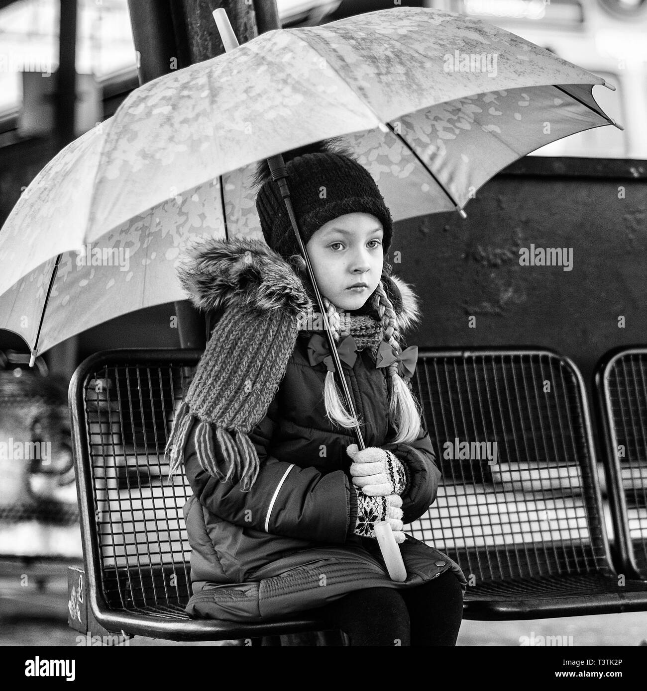 Little child sitting on platform with an umbrella on a railway train ...