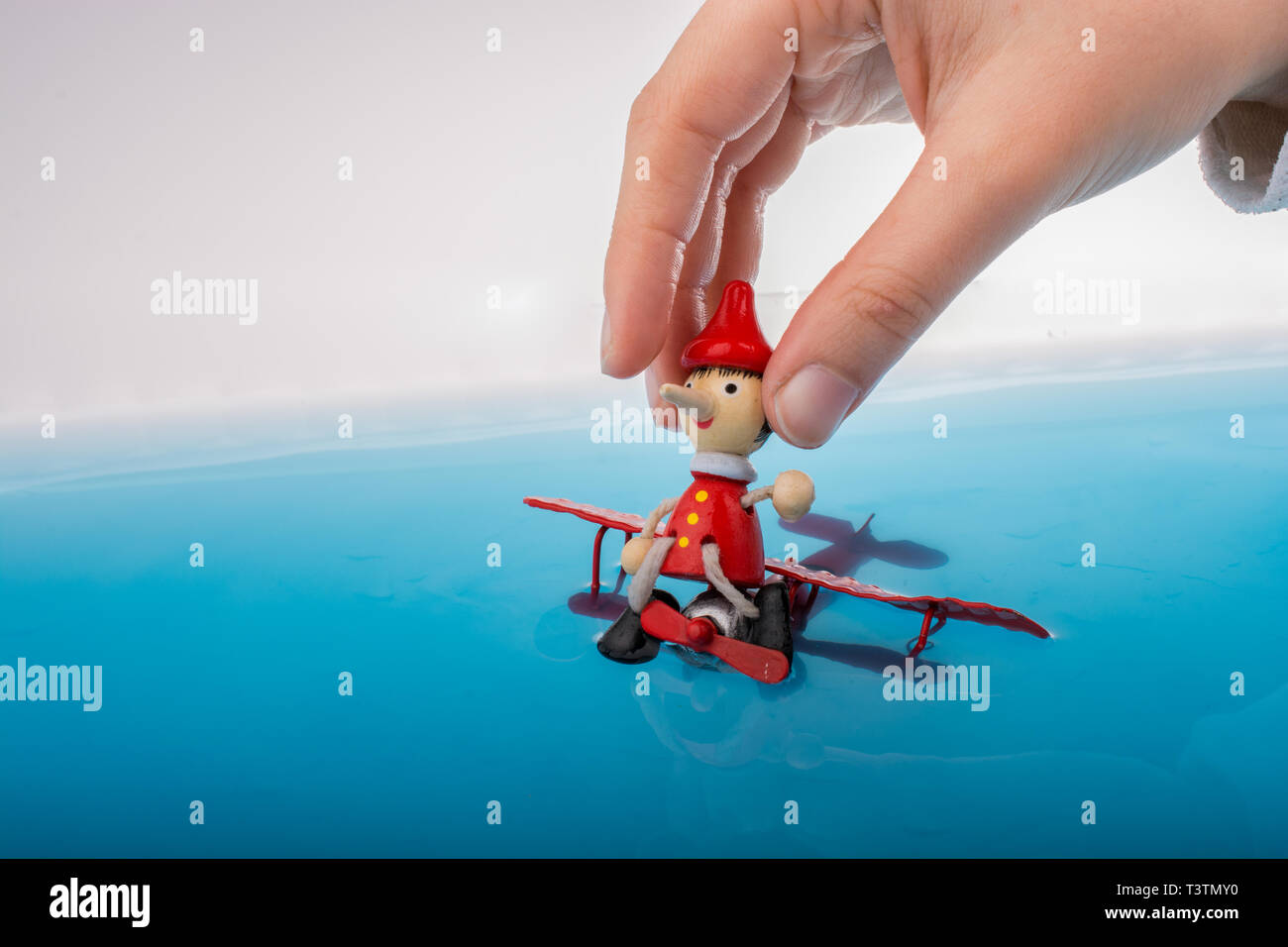 Hand holding Pinocchio on a model airplane in water Stock Photo - Alamy