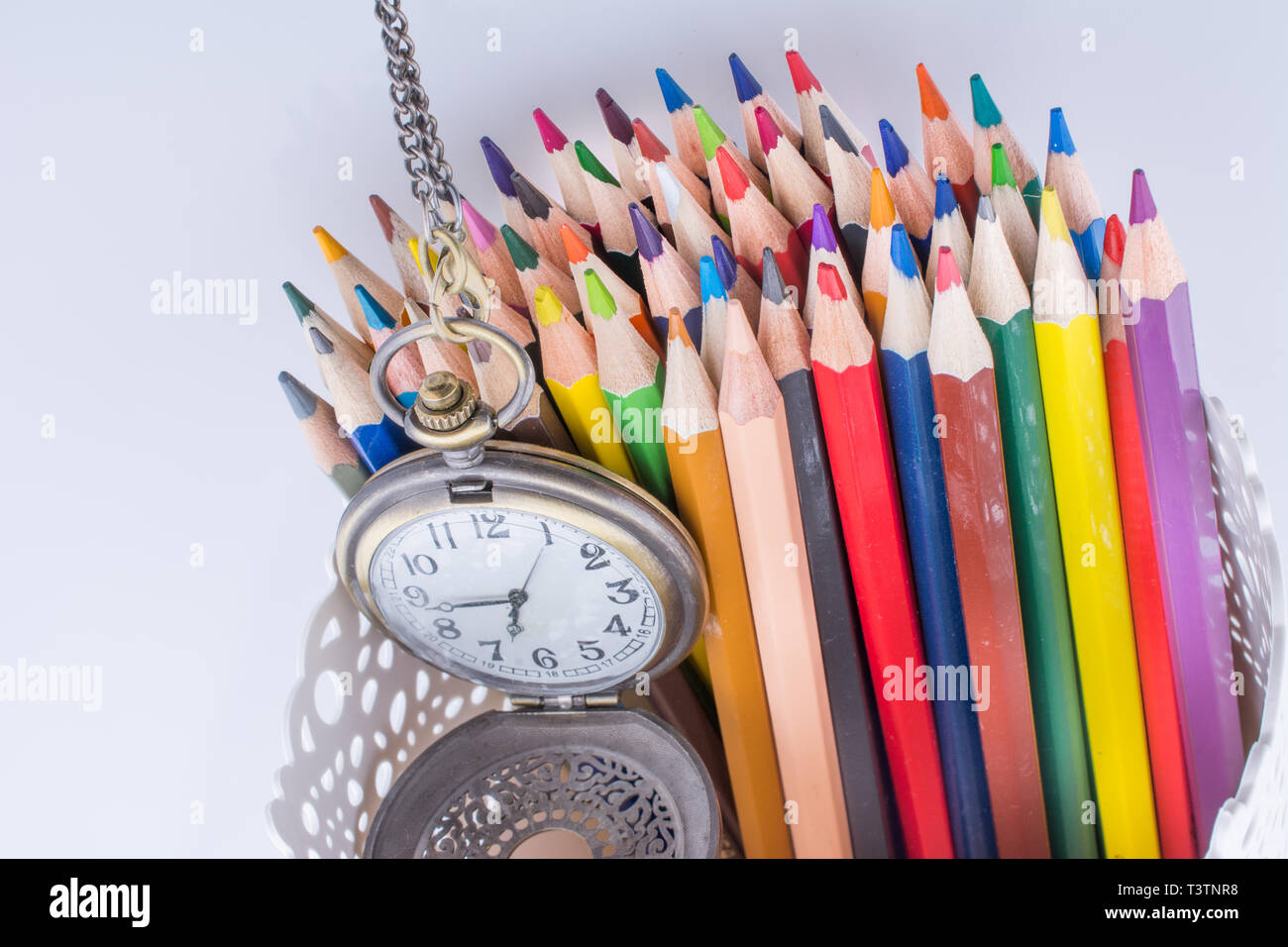Retro style classic pocket watch and color pencils on white background ...