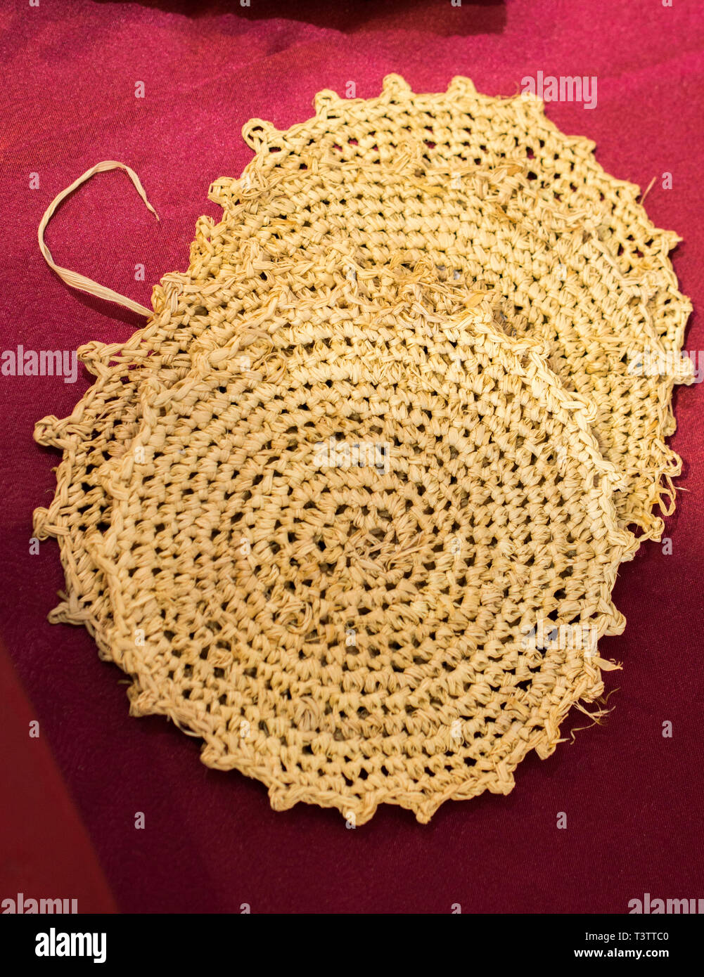 Four straw trivets on a red background on display Stock Photo - Alamy
