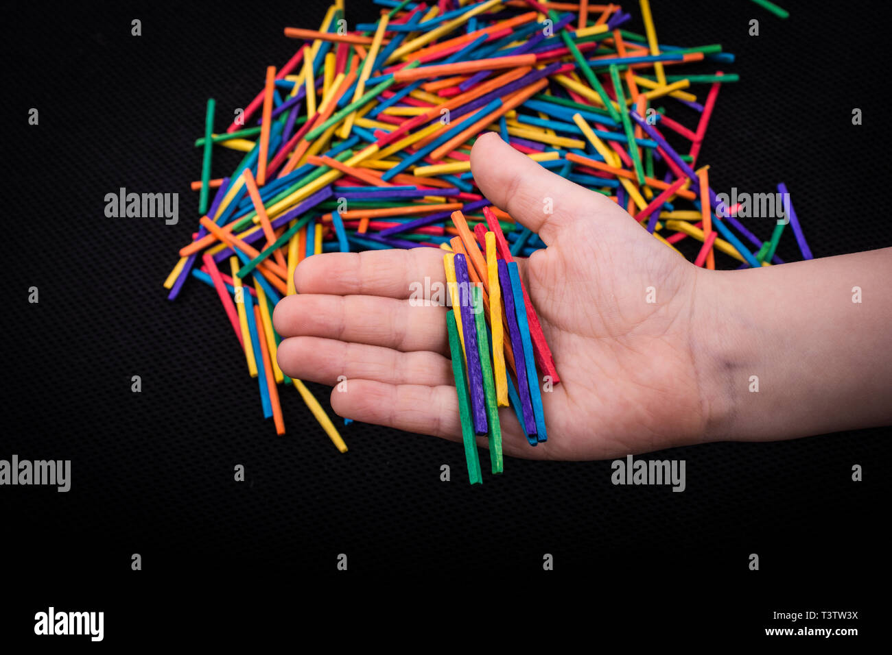 Kid playing with coloured wooden sticks for creativity on white ...
