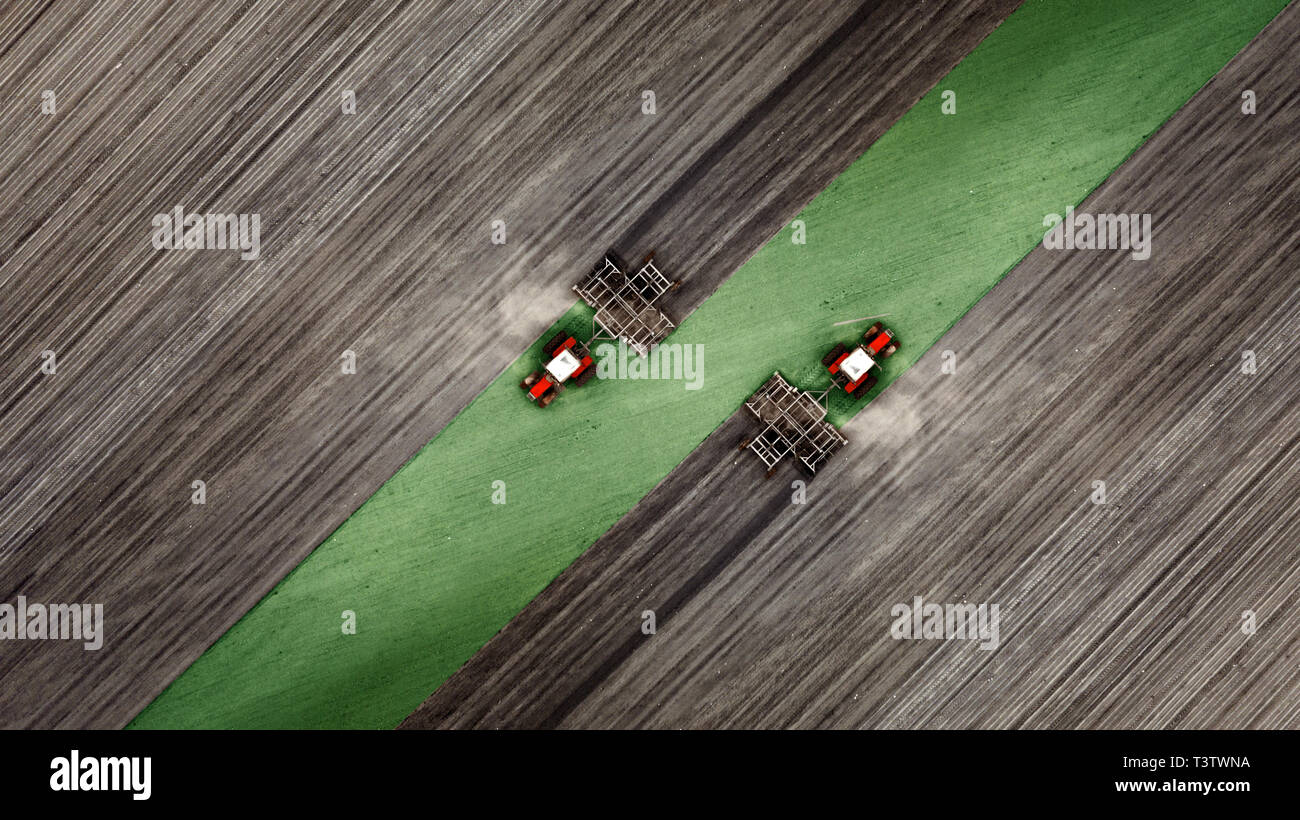 Aerial top view of a tractor, combine harvester plowing agricultural ...