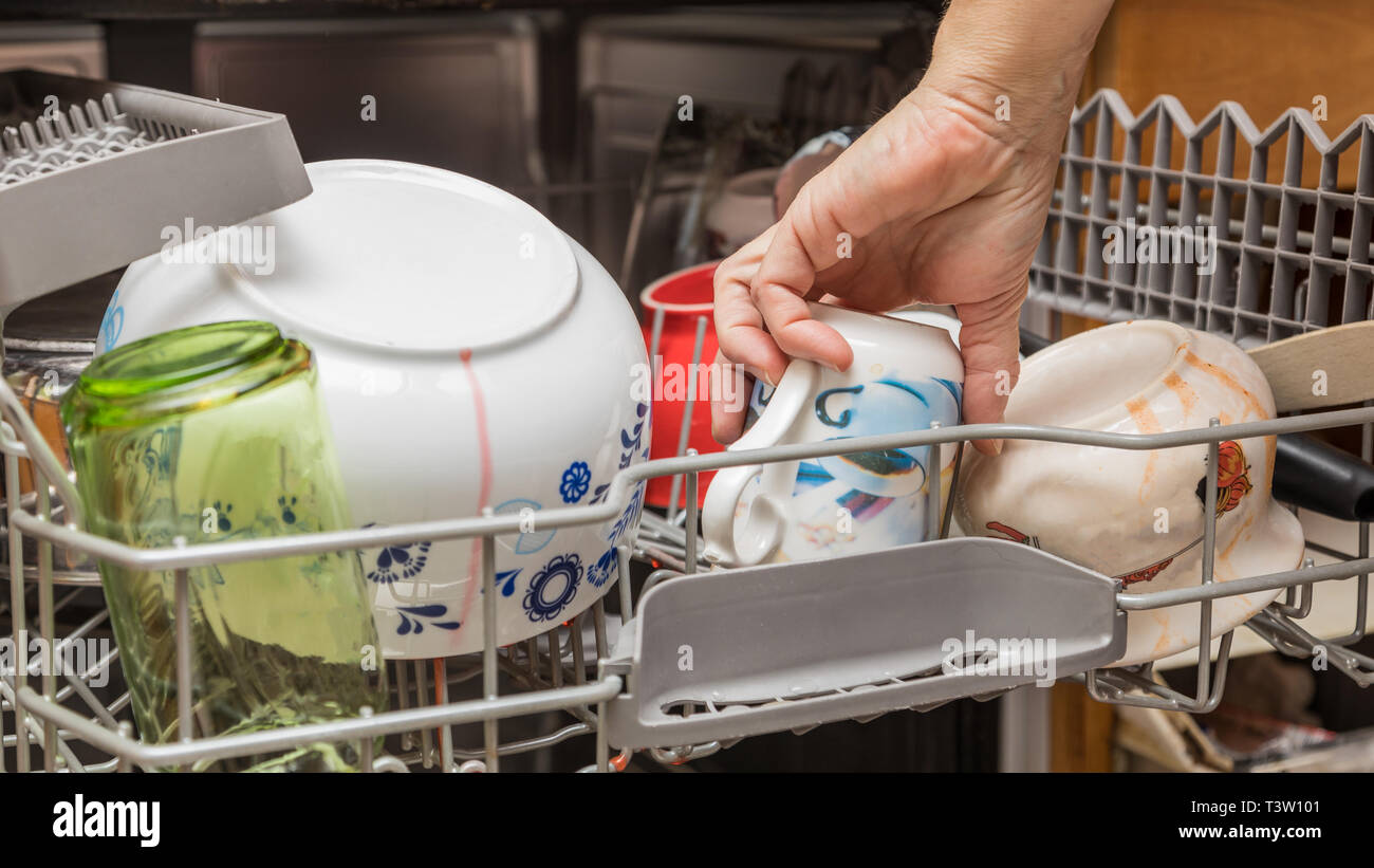 One hand loads a dishwasher Stock Photo - Alamy
