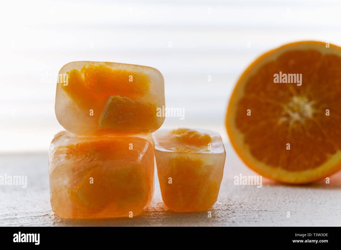 Close Up of Small Pieces of Orange Fruit Frozen in Ice Cubes on White ...