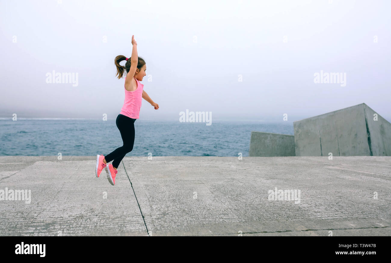 Little girl jumping by sea pier Stock Photo - Alamy
