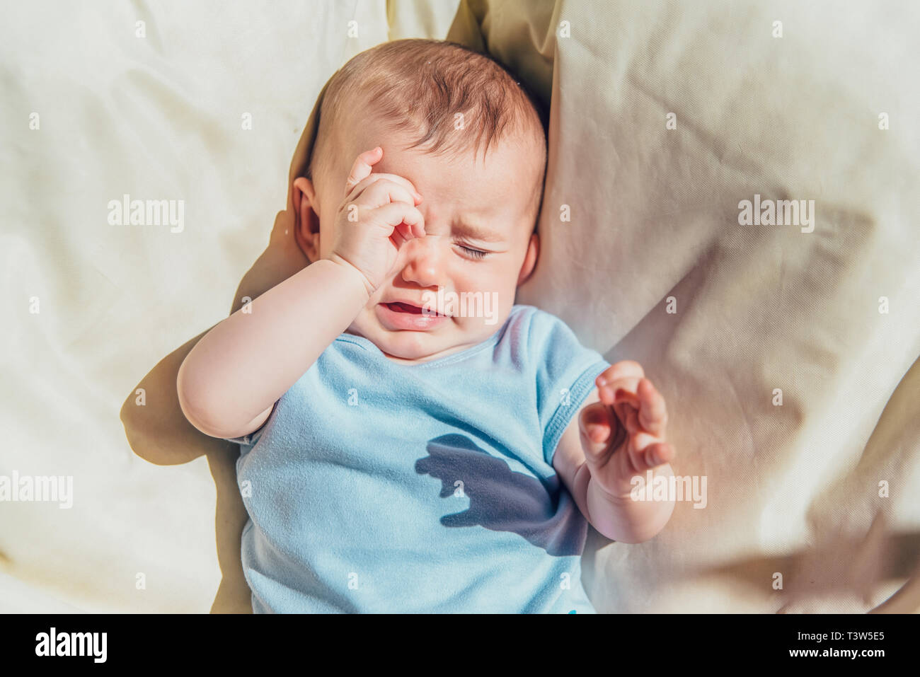 Baby lying in the sun angry and crying calling his parents Stock Photo ...