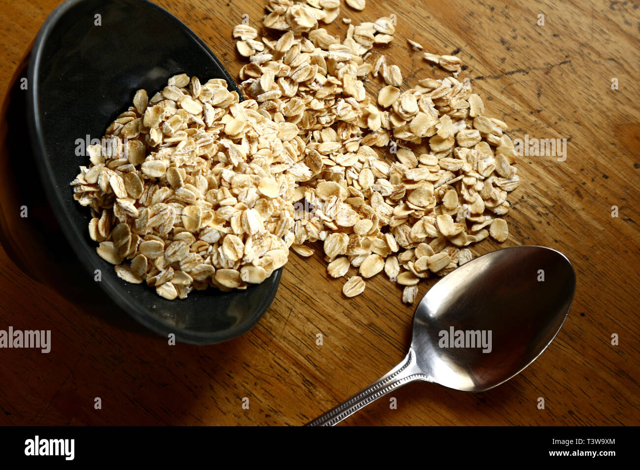Photo of raw whole grain rolled oats spilled from a bowl Stock Photo ...