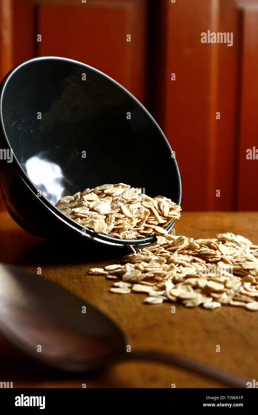 Photo of raw whole grain rolled oats spilled from a bowl Stock Photo ...