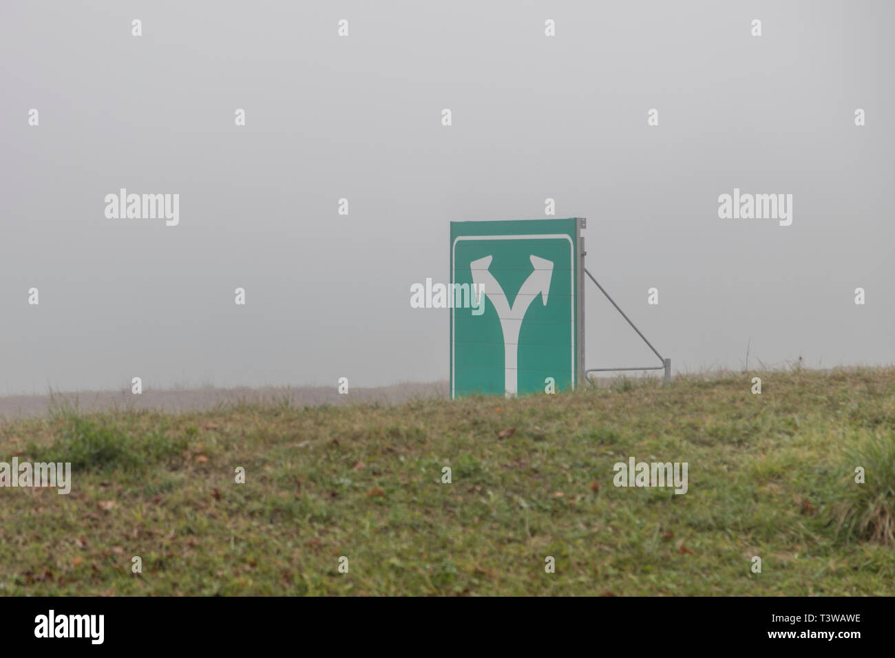 A highway streetsign showing the road splitting is partially obscured ...