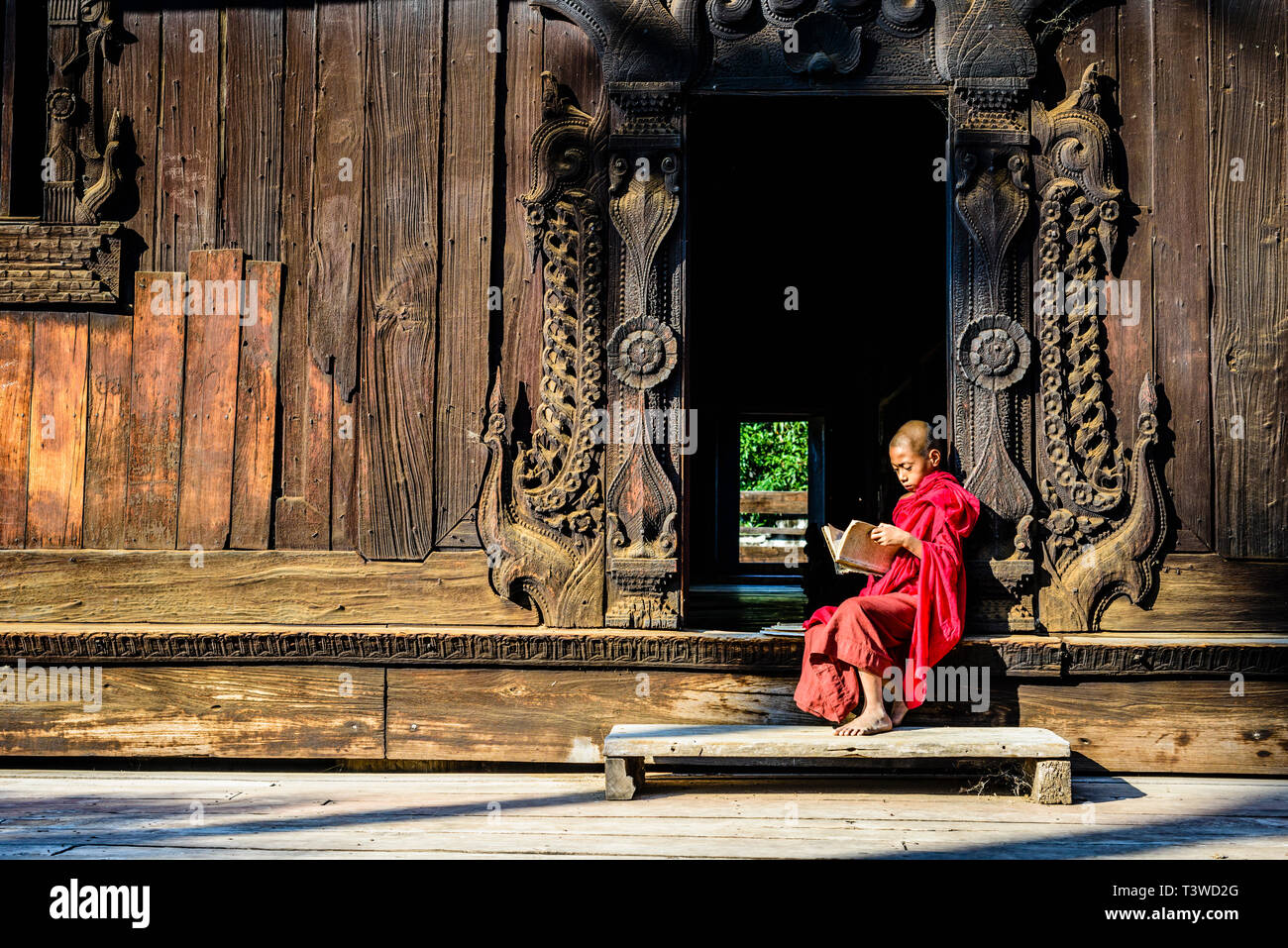 Asian monk reading by ornate doorway to temple Stock Photo - Alamy
