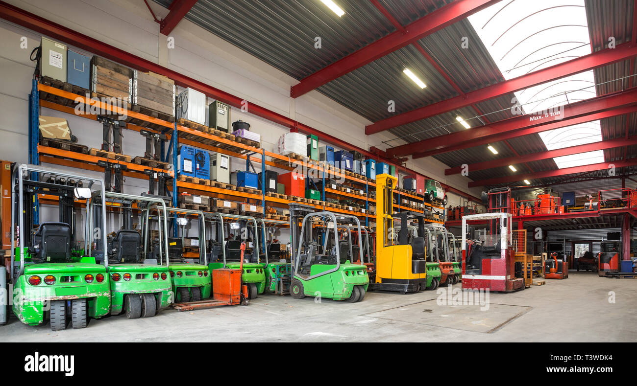 Forklift machinery in a row in warehouse Stock Photo - Alamy