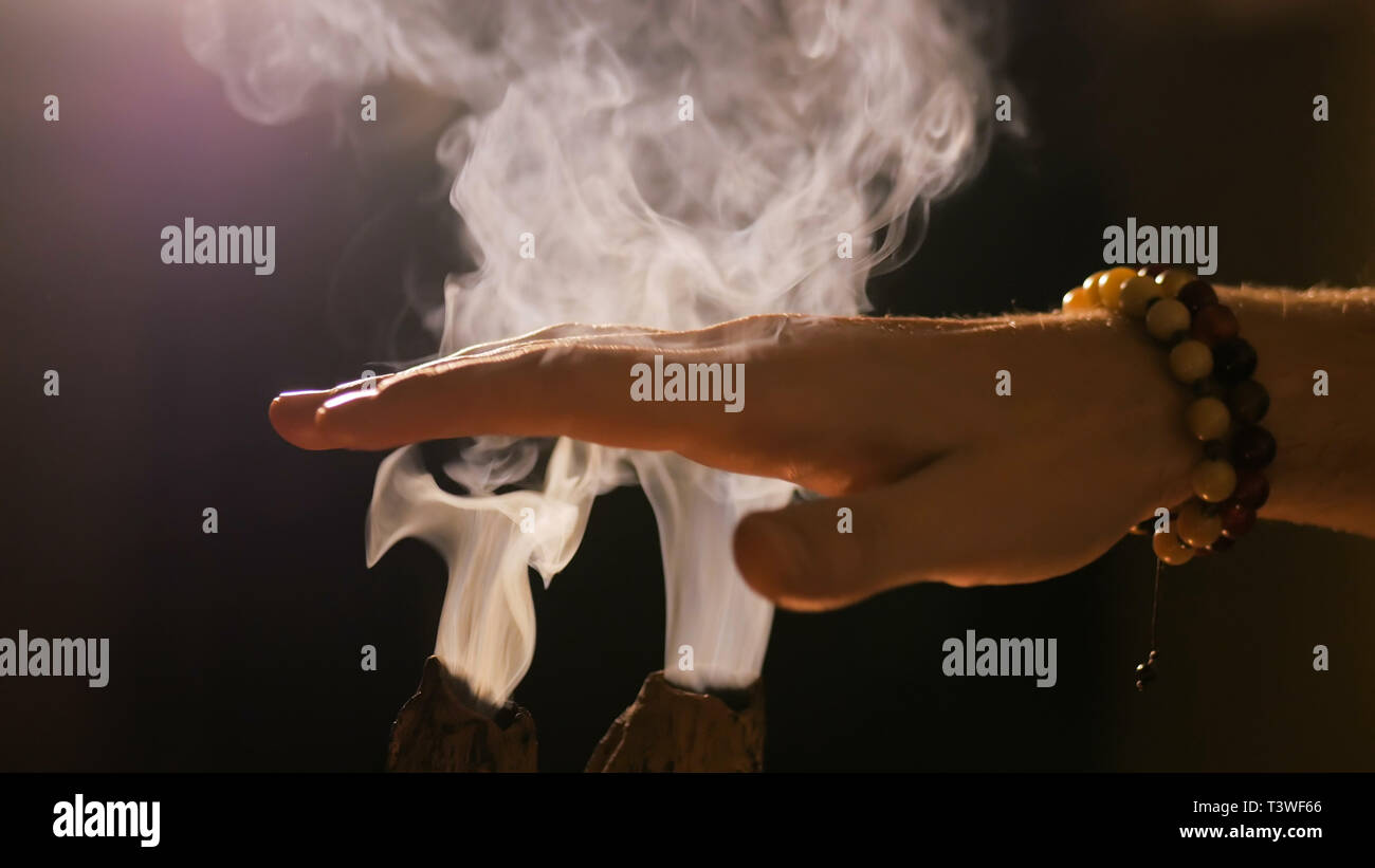 Smoke from incense rises through fingers Stock Photo - Alamy