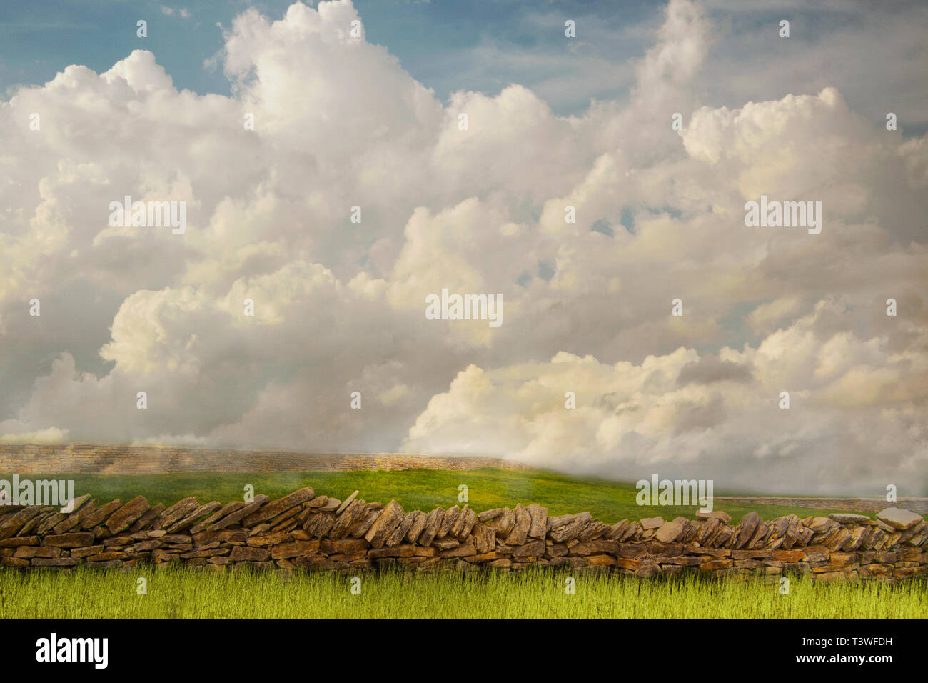 Stone wall and grassy fields under clouds in rural landscape Stock ...