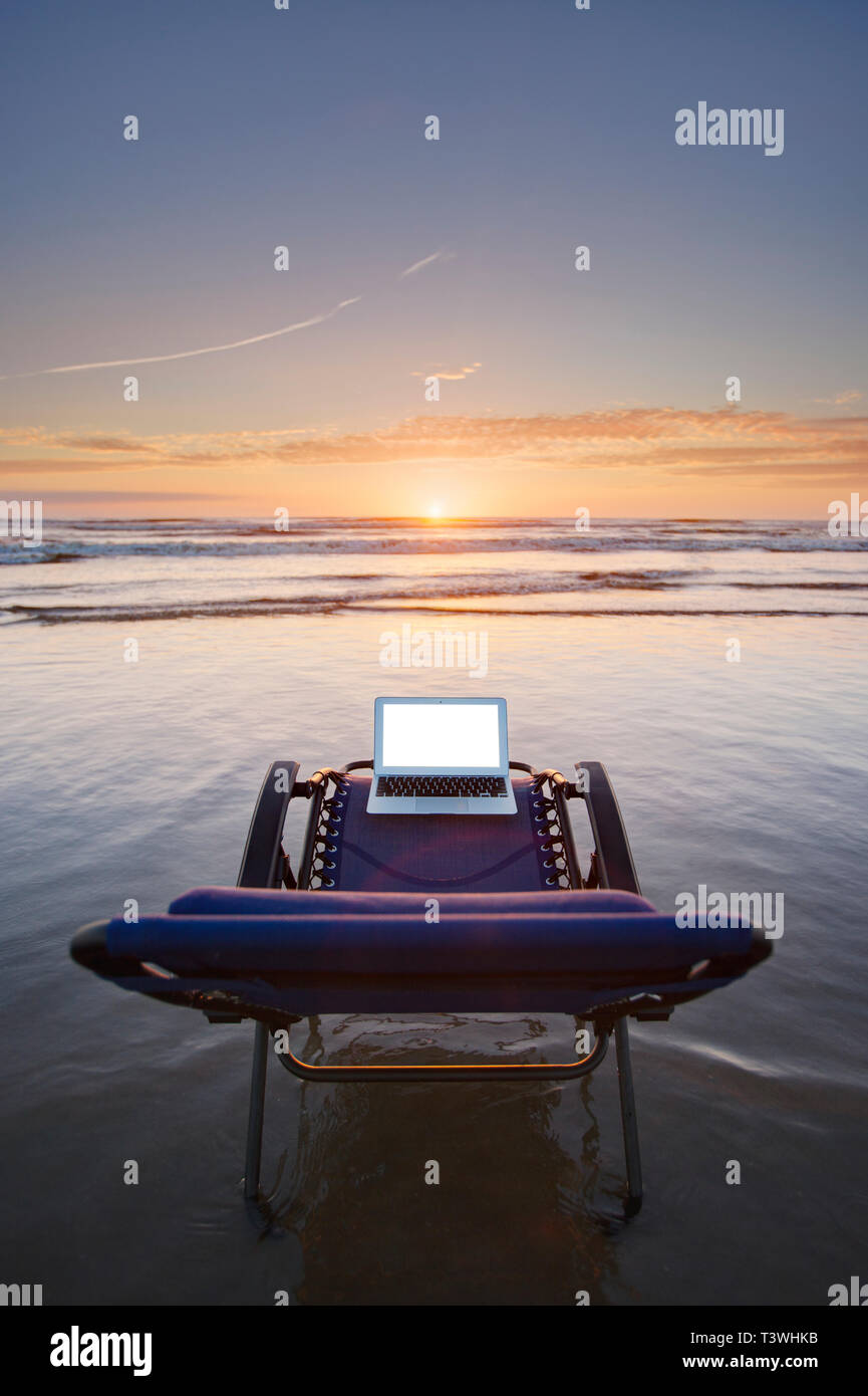 Laptop on deck chair overlooking sunset on beach Stock Photo - Alamy