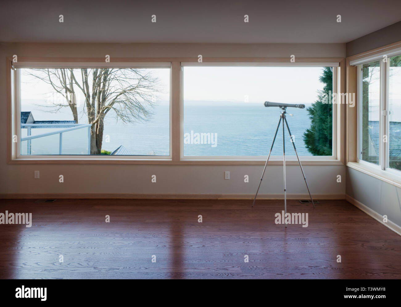 Telescope looking out living room window to ocean Stock Photo - Alamy