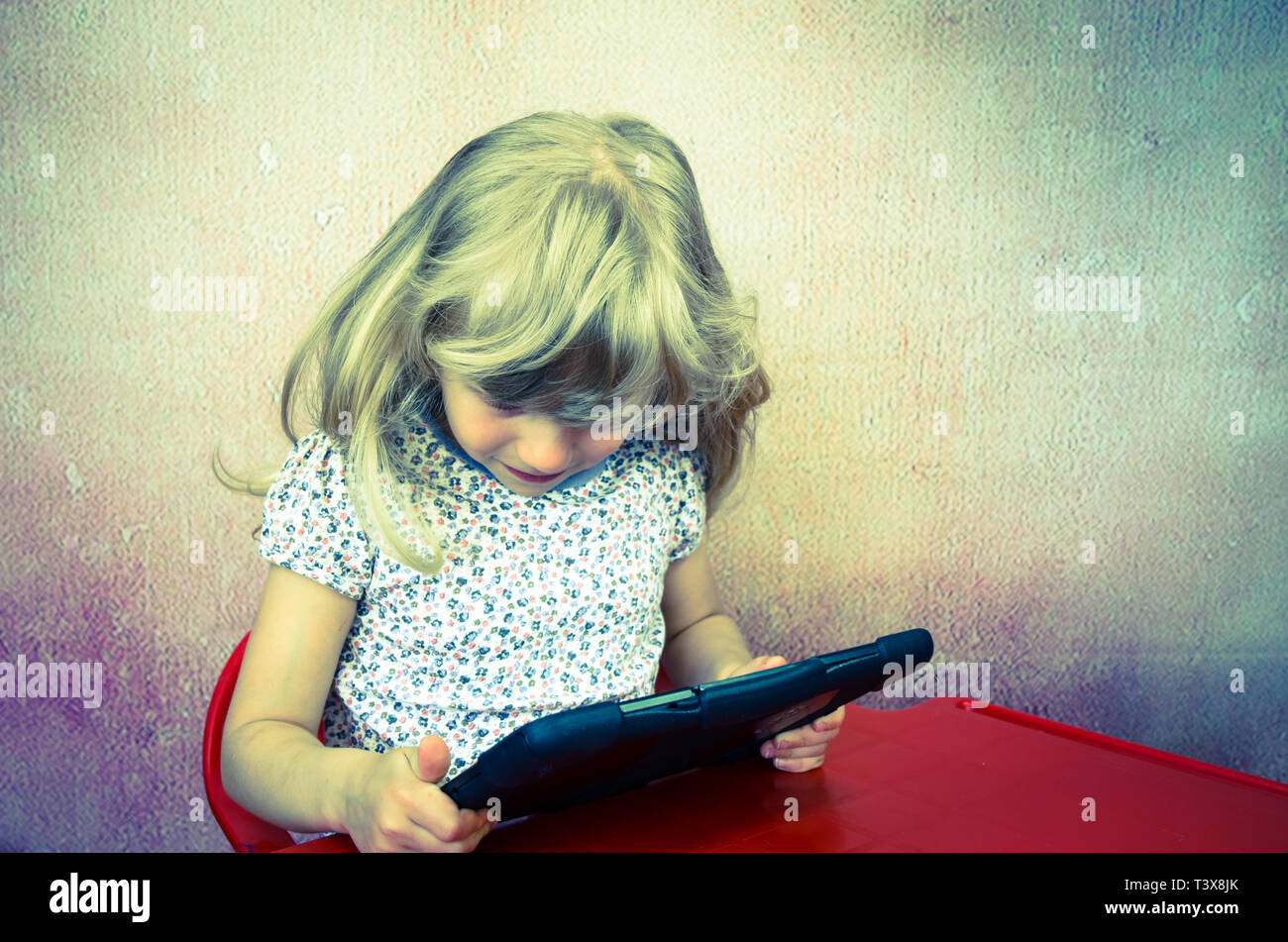 concentrated little blond girl working with tablet Stock Photo - Alamy