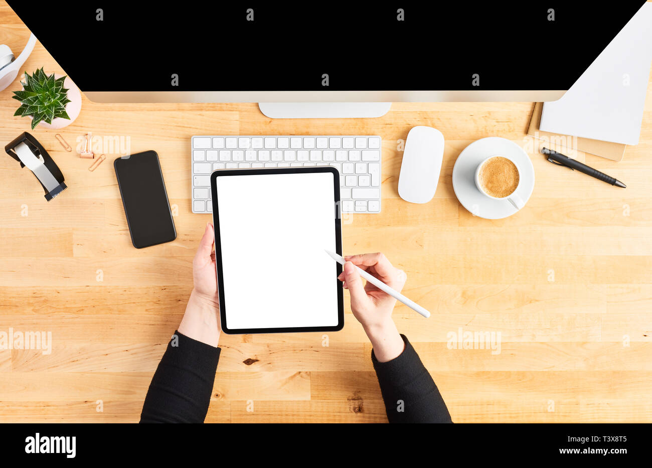 Female hands holding digital tablet and pencil. Top view of wooden ...