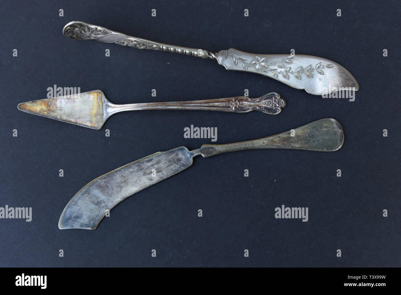 Weathered silverware of multiple sizes and patterns are arranged ...