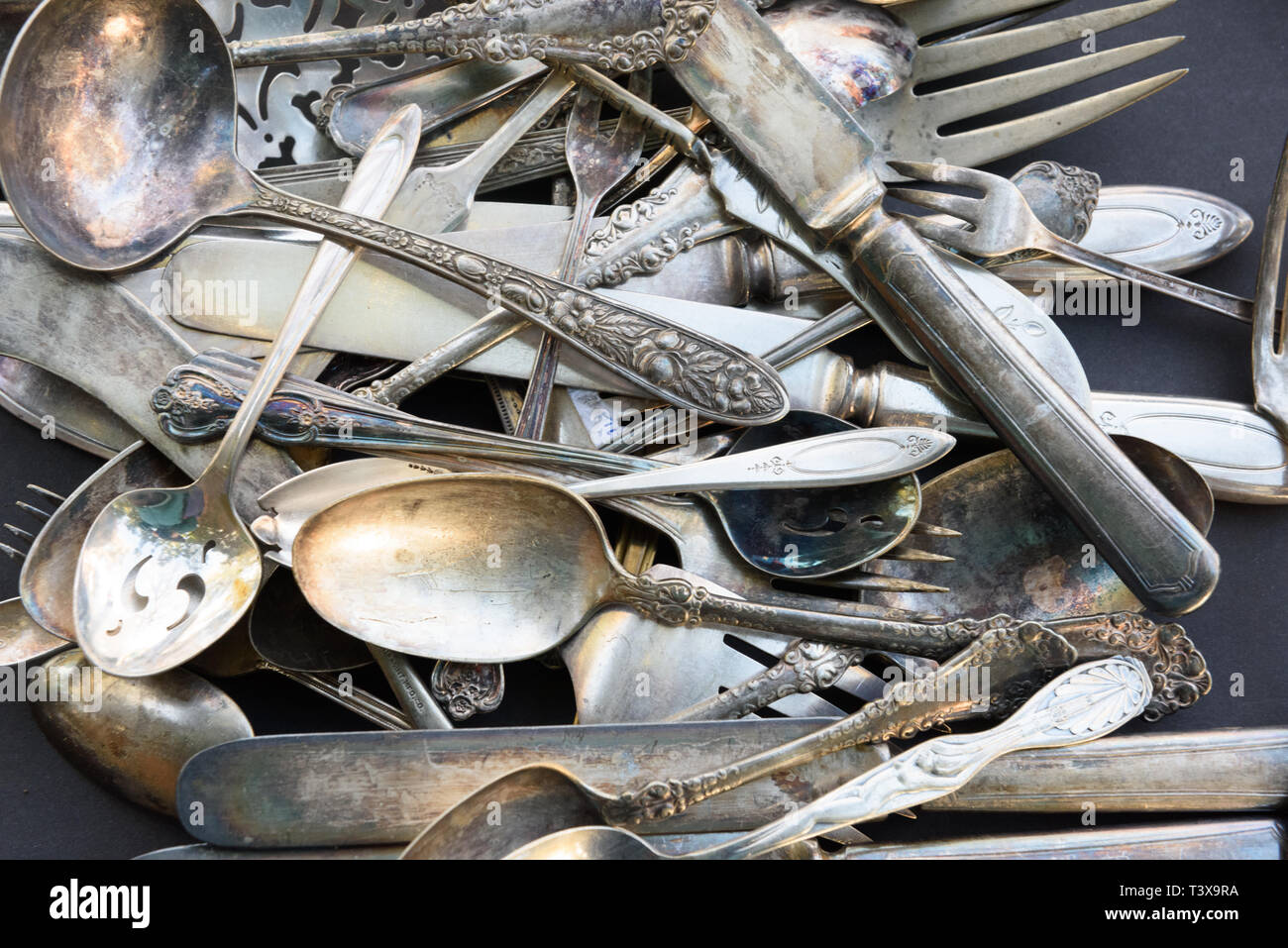 Weathered silverware of multiple sizes and patterns are arranged ...