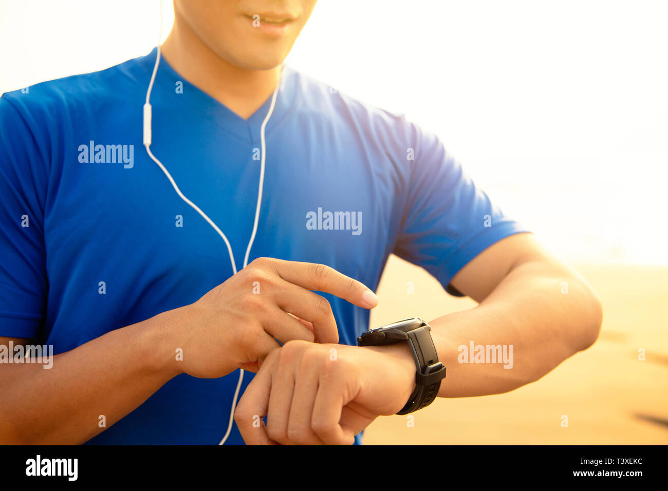 young Man running on beach and checking Heart Rate Monitor On watch ...