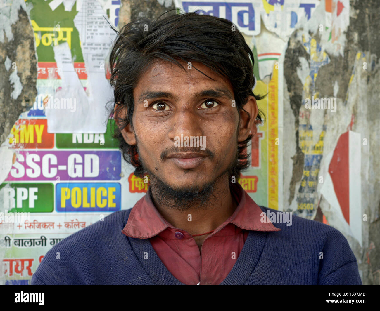 Scruffy, young Indian dalit man poses for the camera in front of a ...