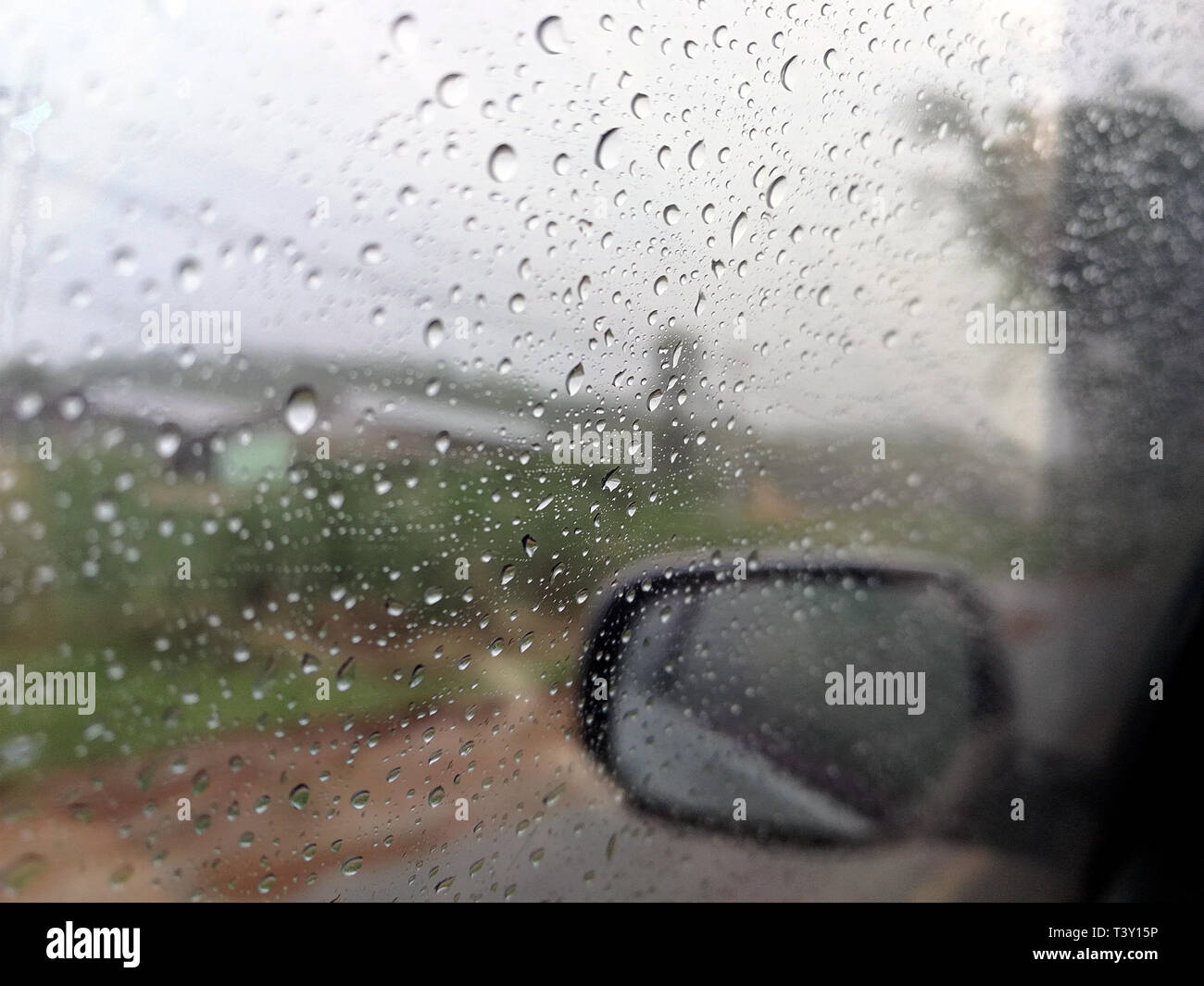 Rain drops on the car glass window with road in rainy season abstract ...