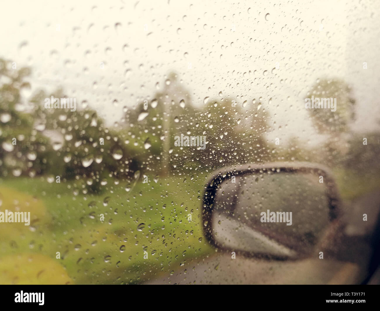 Rain drops on the car glass window with road in rainy season abstract ...