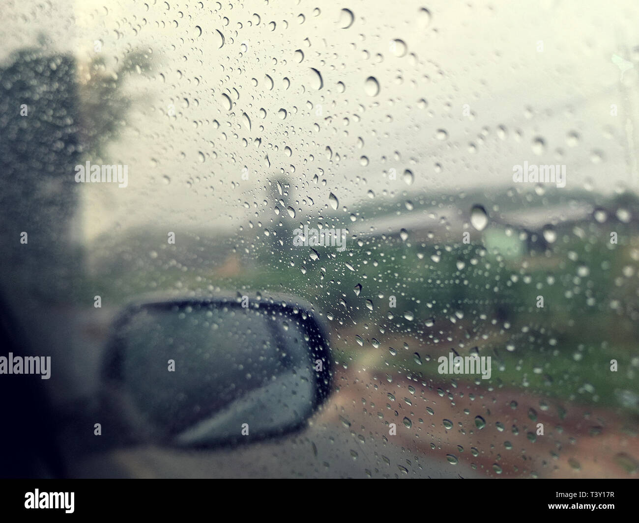 Rain drops on the car glass window with road in rainy season abstract ...