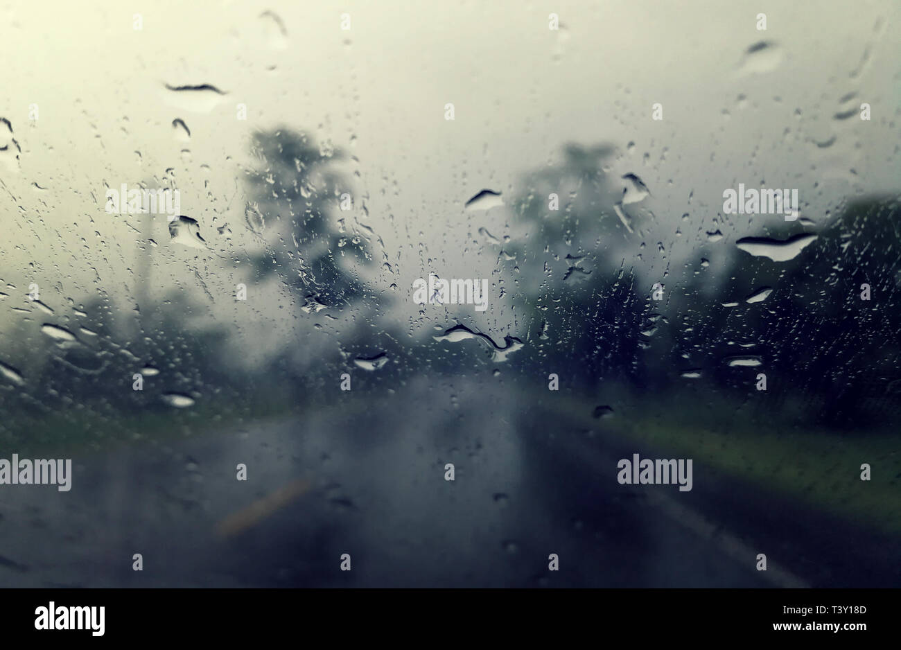 Rain drops on the car glass window with road in rainy season abstract ...
