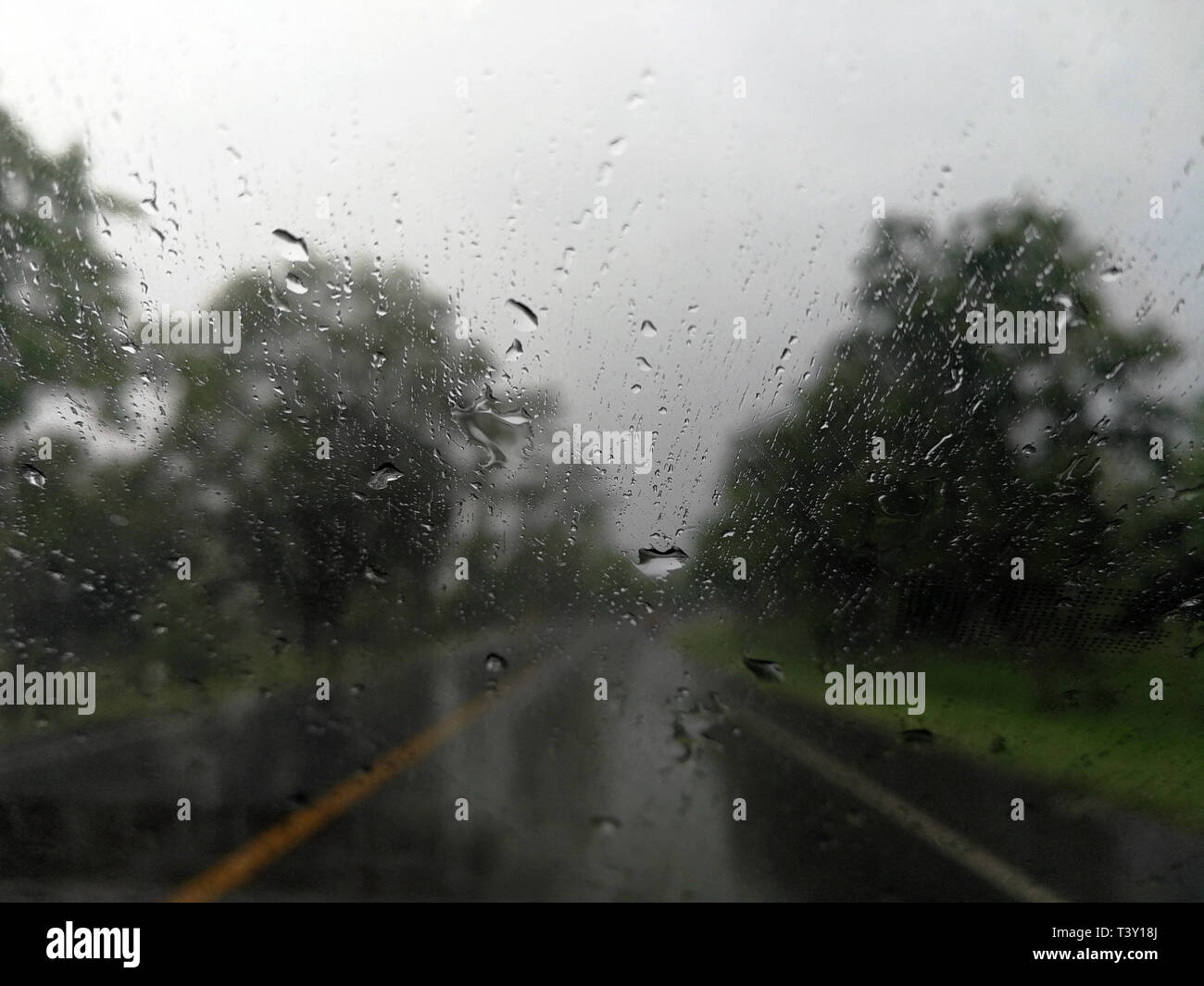 Rain drops on the car glass window with road in rainy season abstract ...