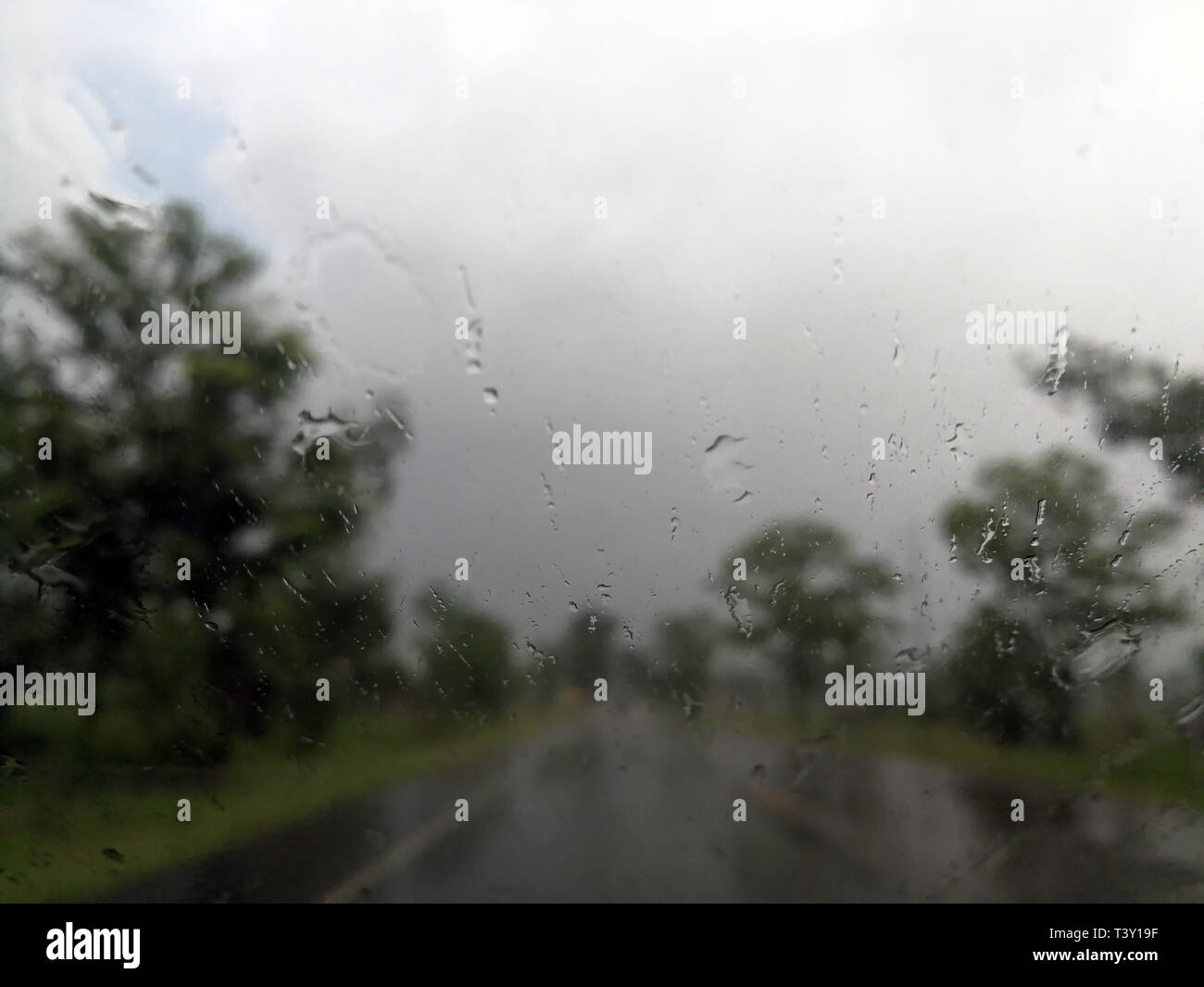 Rain drops on the car glass window with road in rainy season abstract ...