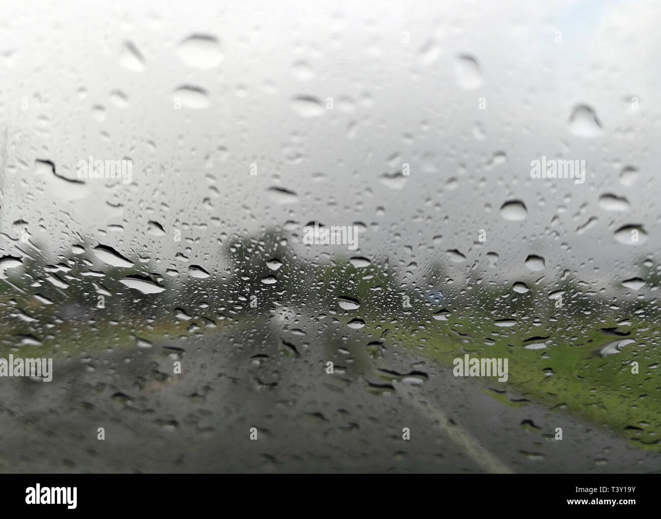 Rain drops on the car glass window with road in rainy season abstract ...