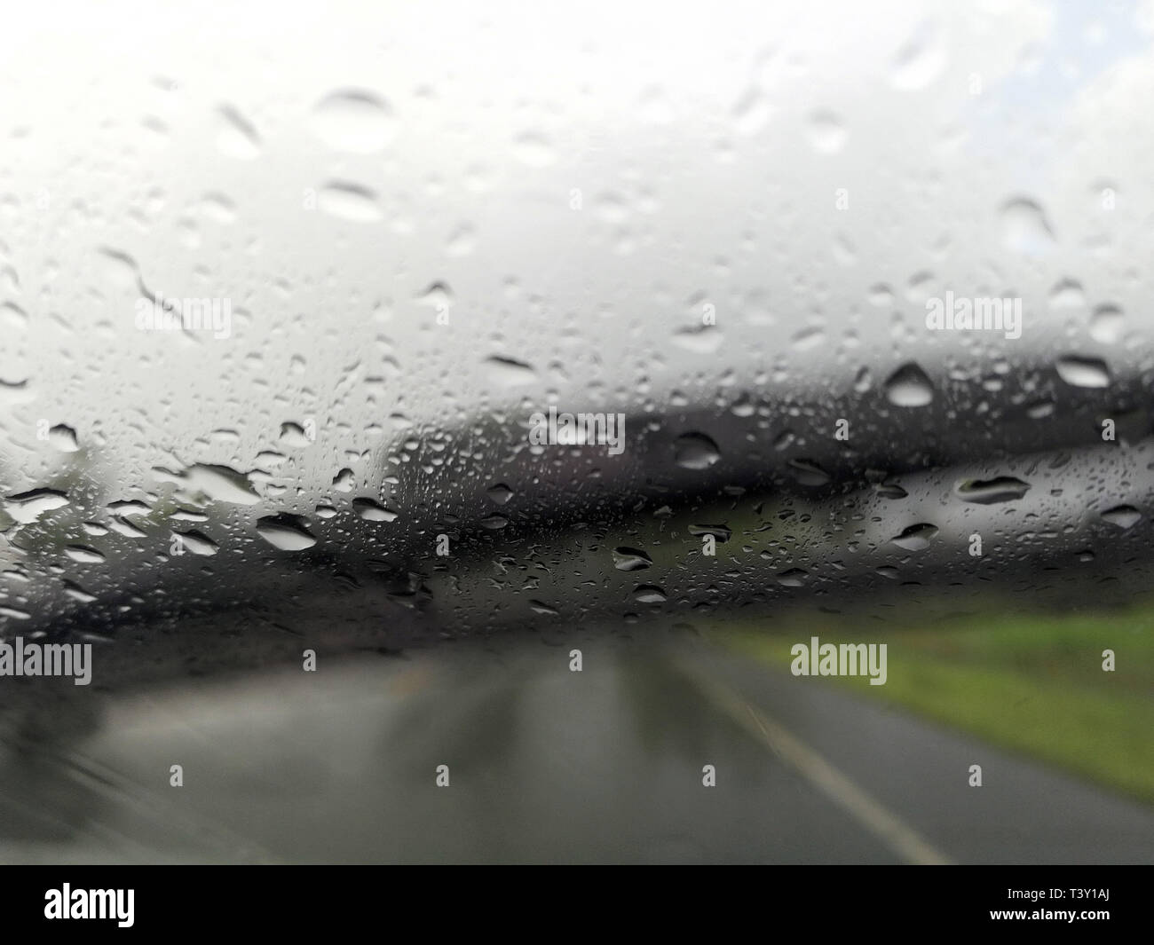 Rain drops on the car glass window with road in rainy season abstract ...