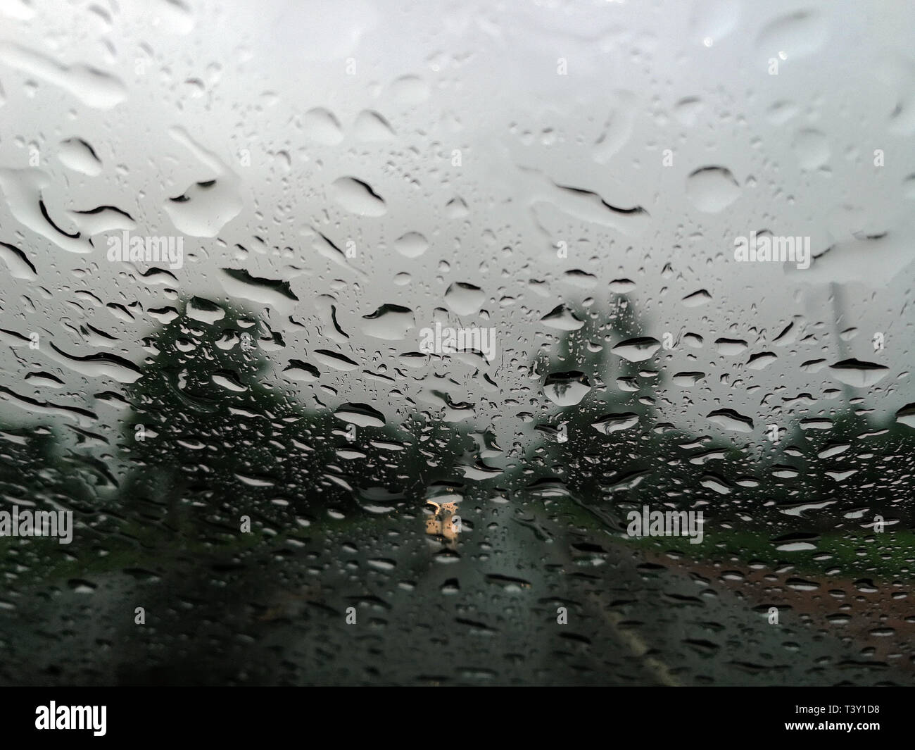 Rain drops on the car glass window with road in rainy season abstract ...