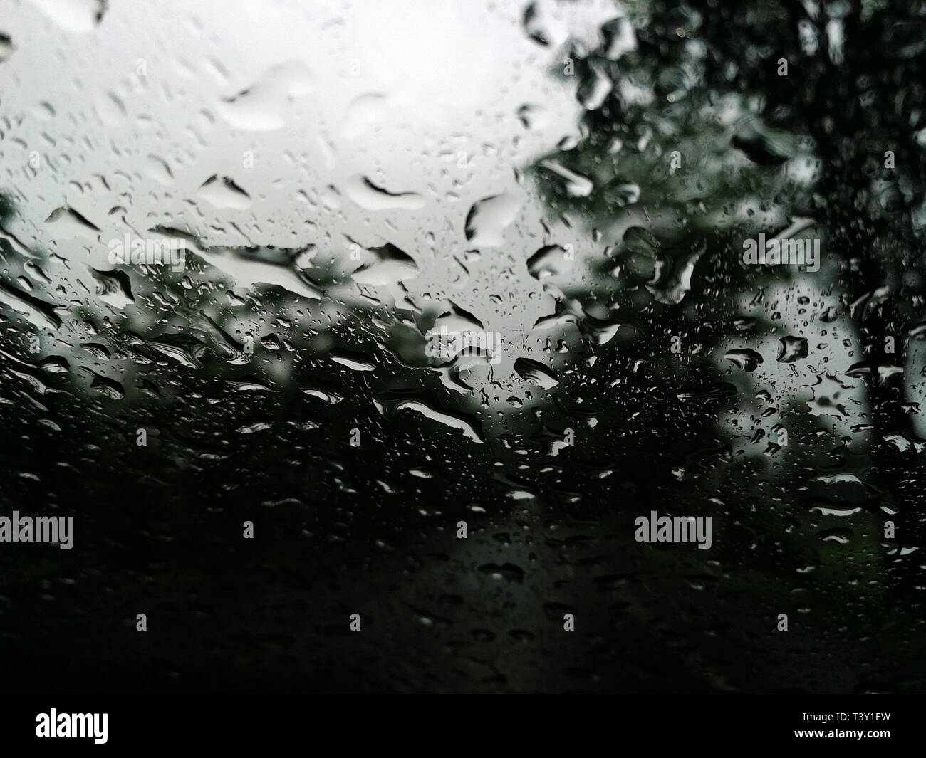 Rain drops on the car glass window with road in rainy season abstract ...