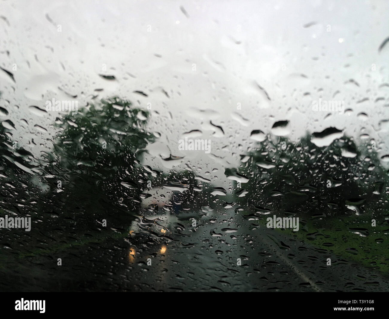 Rain drops on the car glass window with road in rainy season abstract ...