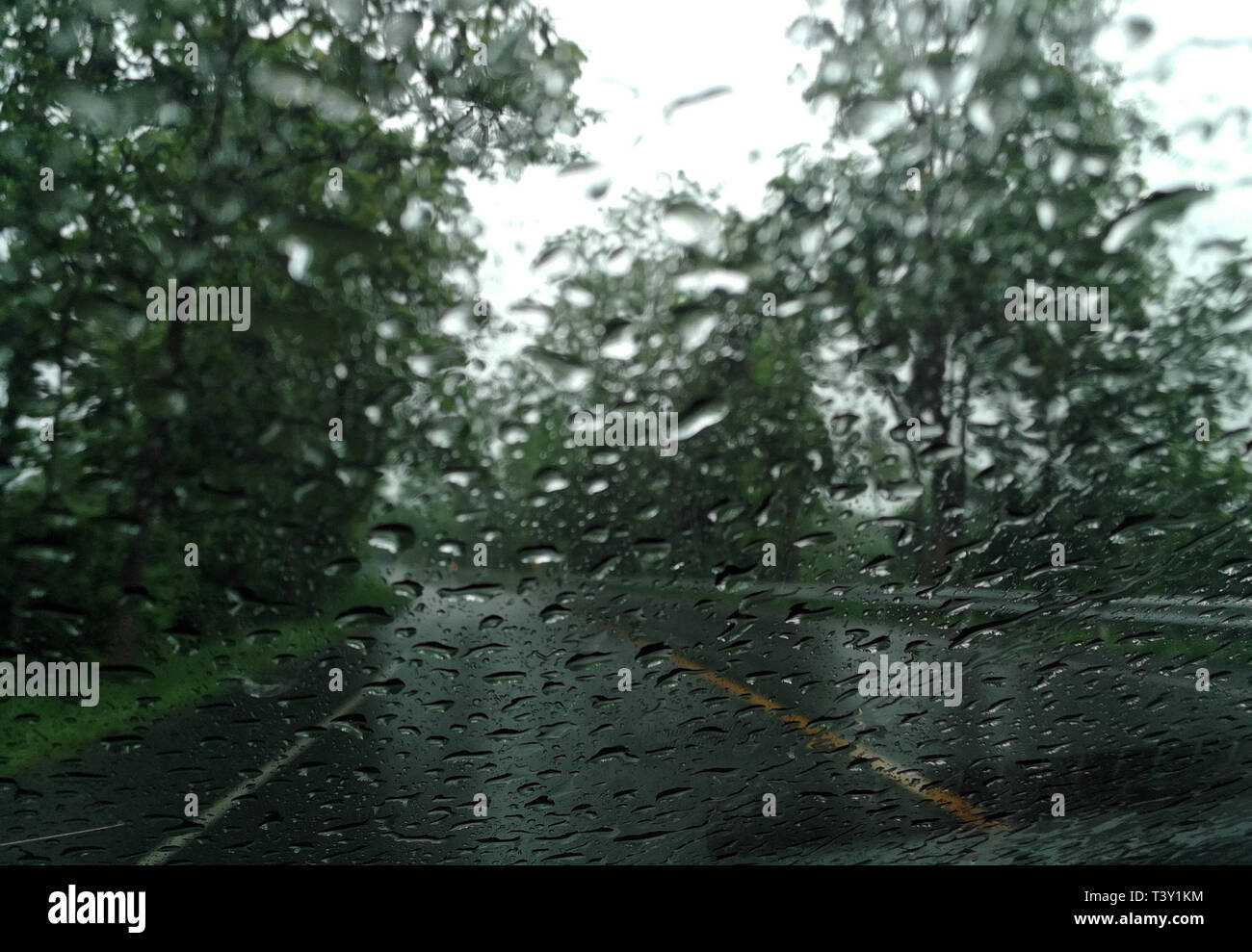 Rain drops on the car glass window with road in rainy season abstract ...