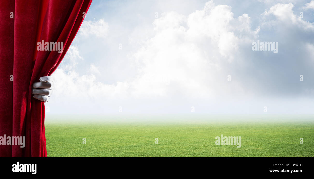 Green meadow behind red curtain and hand holding it Stock Photo - Alamy