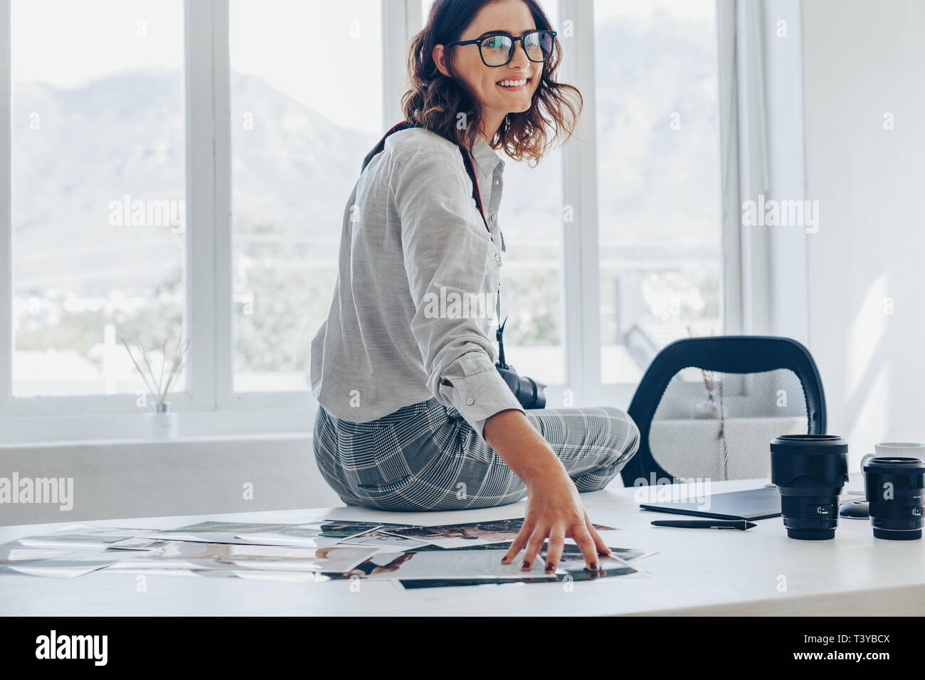 Happy young woman sitting on her and looking at camera. Female ...