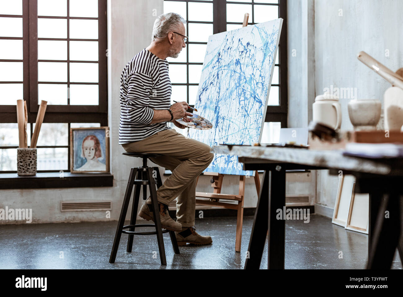 Grey-haired artist. Experienced grey-haired artist wearing striped ...