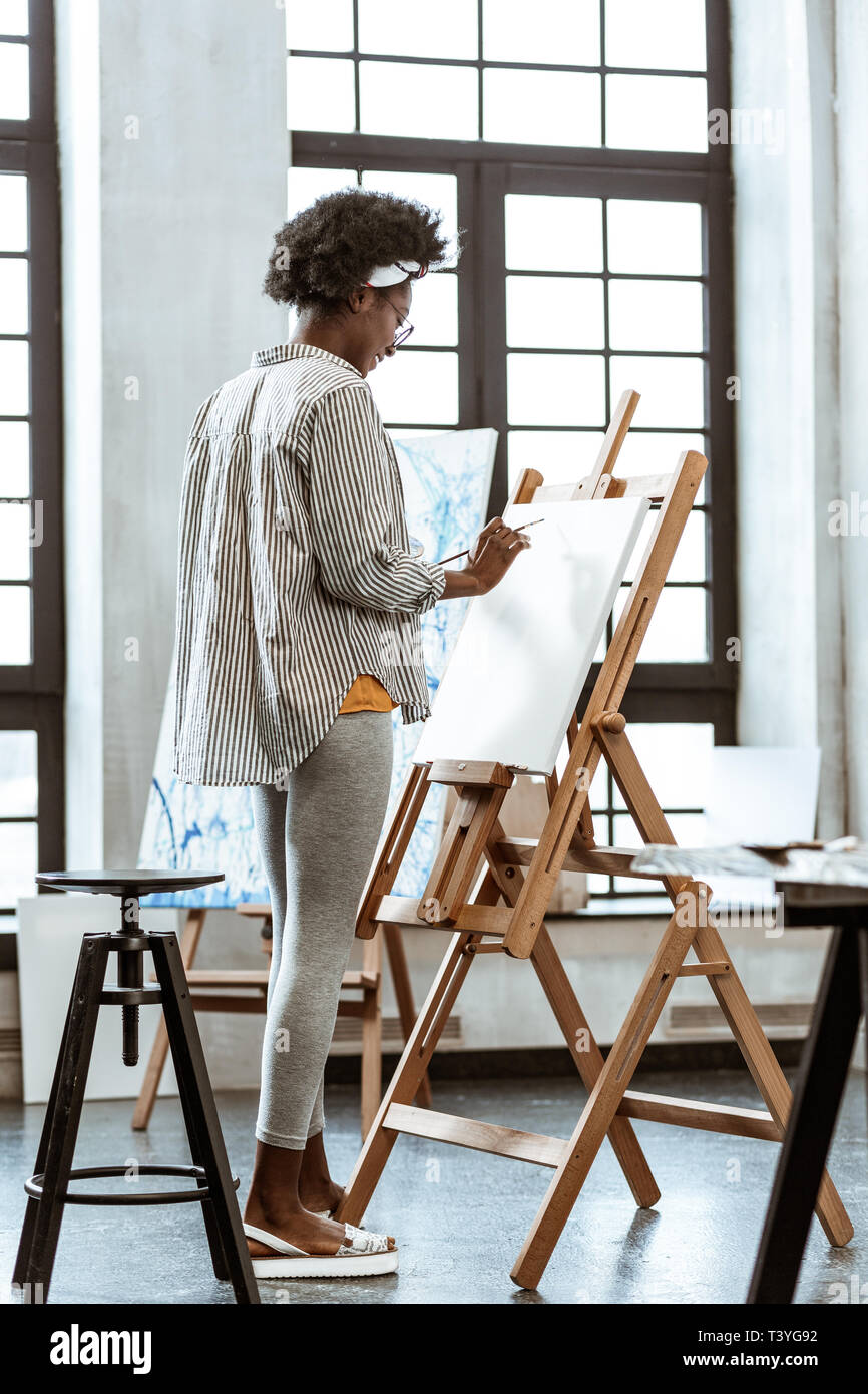 Truly inspired. Young curly artist feeling truly inspired while ...