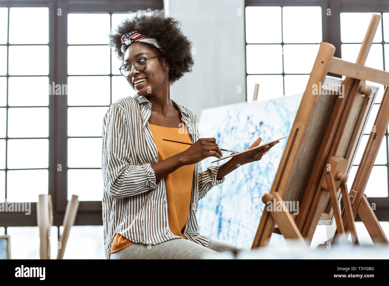 Feeling cheerful. Young African-American artist feeling cheerful while ...