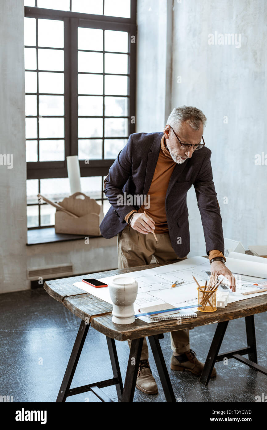 Working hard. Bearded grey-haired interior designer wearing stylish ...