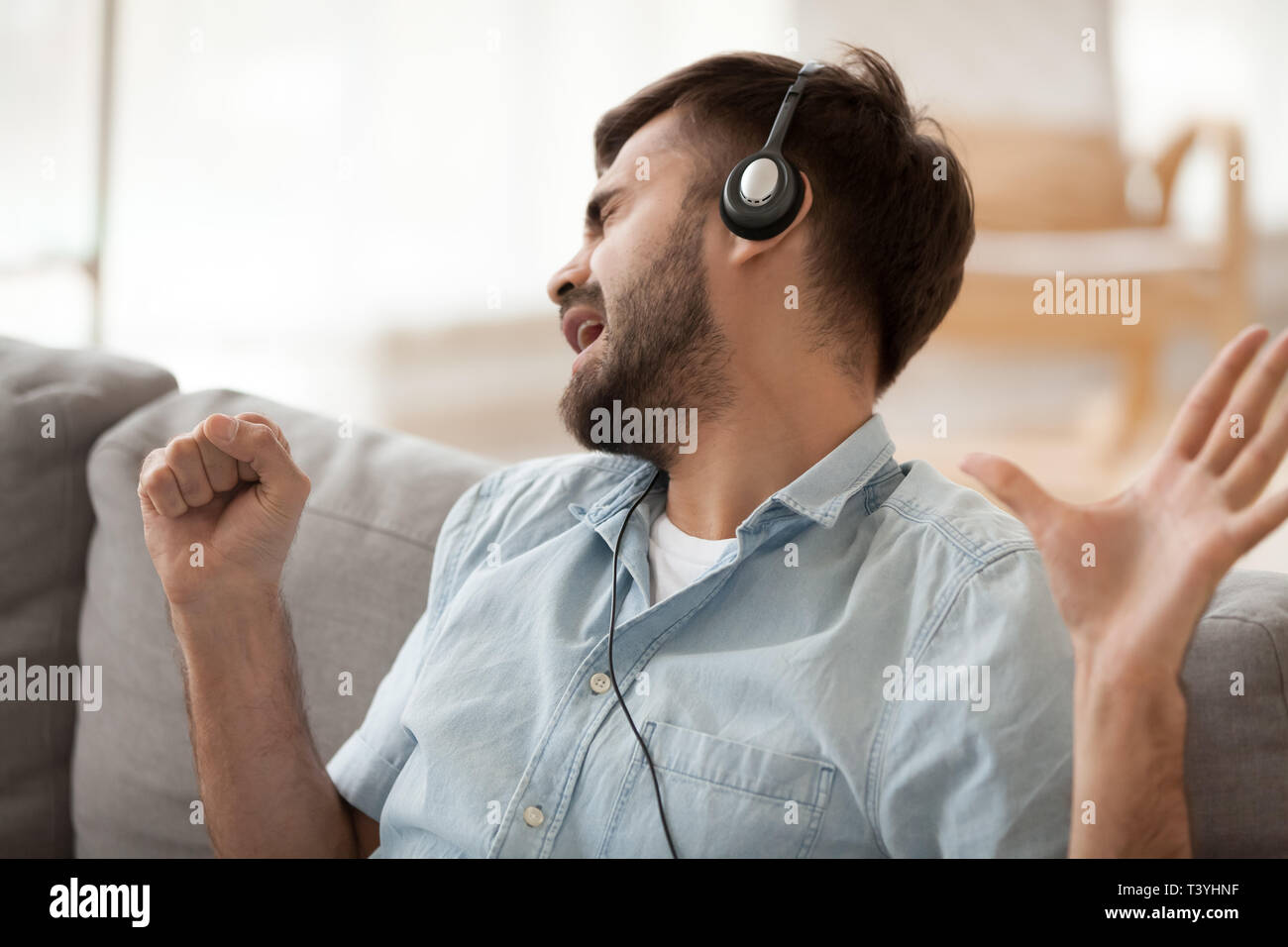 Happy man wearing headphones singing song, imagine microphone in hand ...