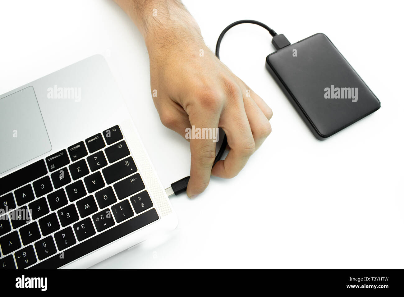 Hand of a person connecting an external hard drive to his laptop on a ...