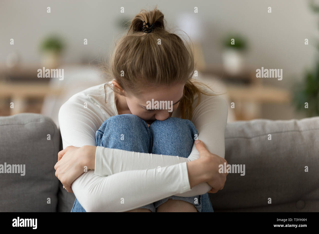 Upset frustrated woman sitting on couch, embrace knees, having problem ...