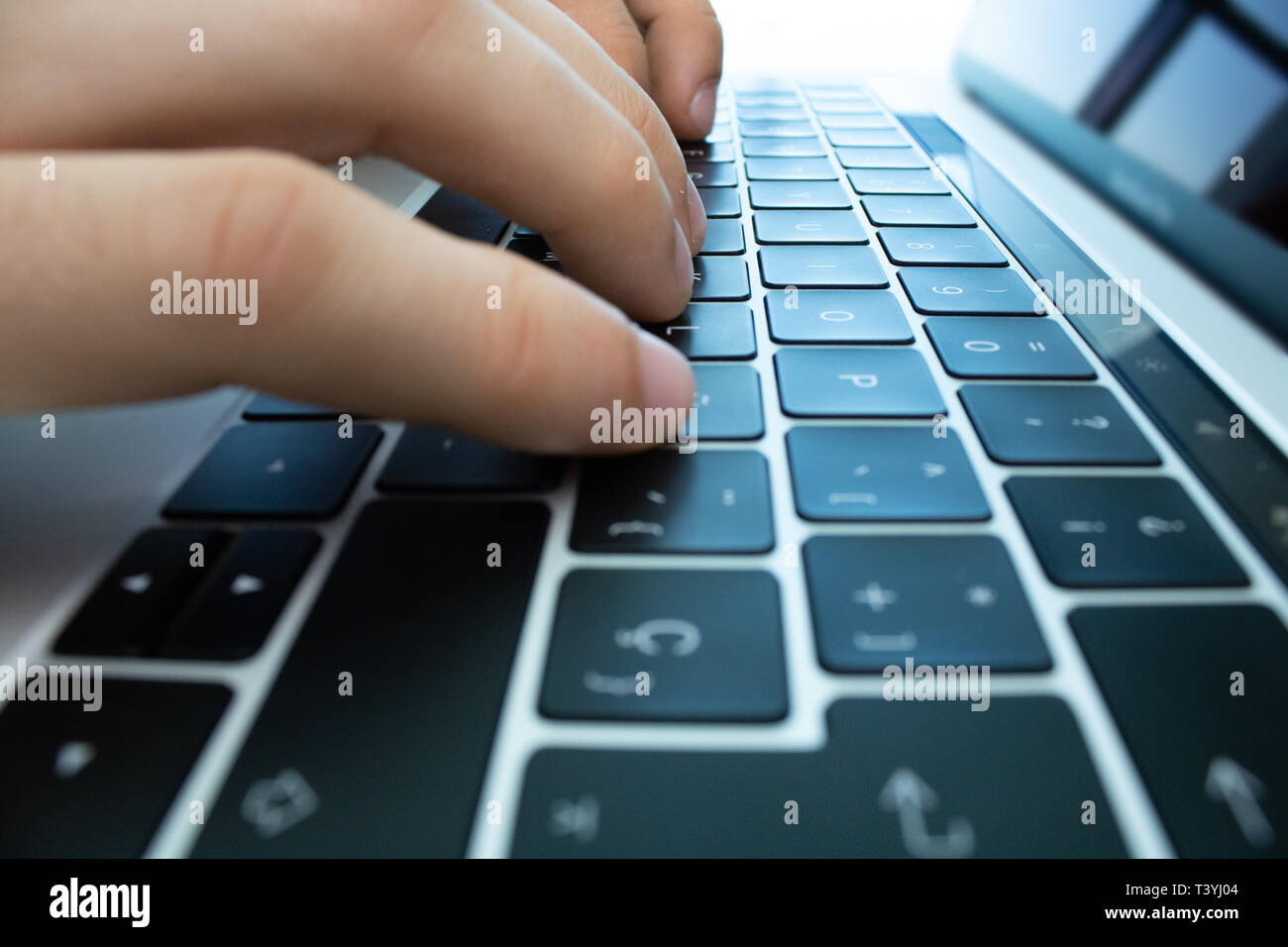 Hands using the keyboard and touchpad of a laptop computer on a white ...