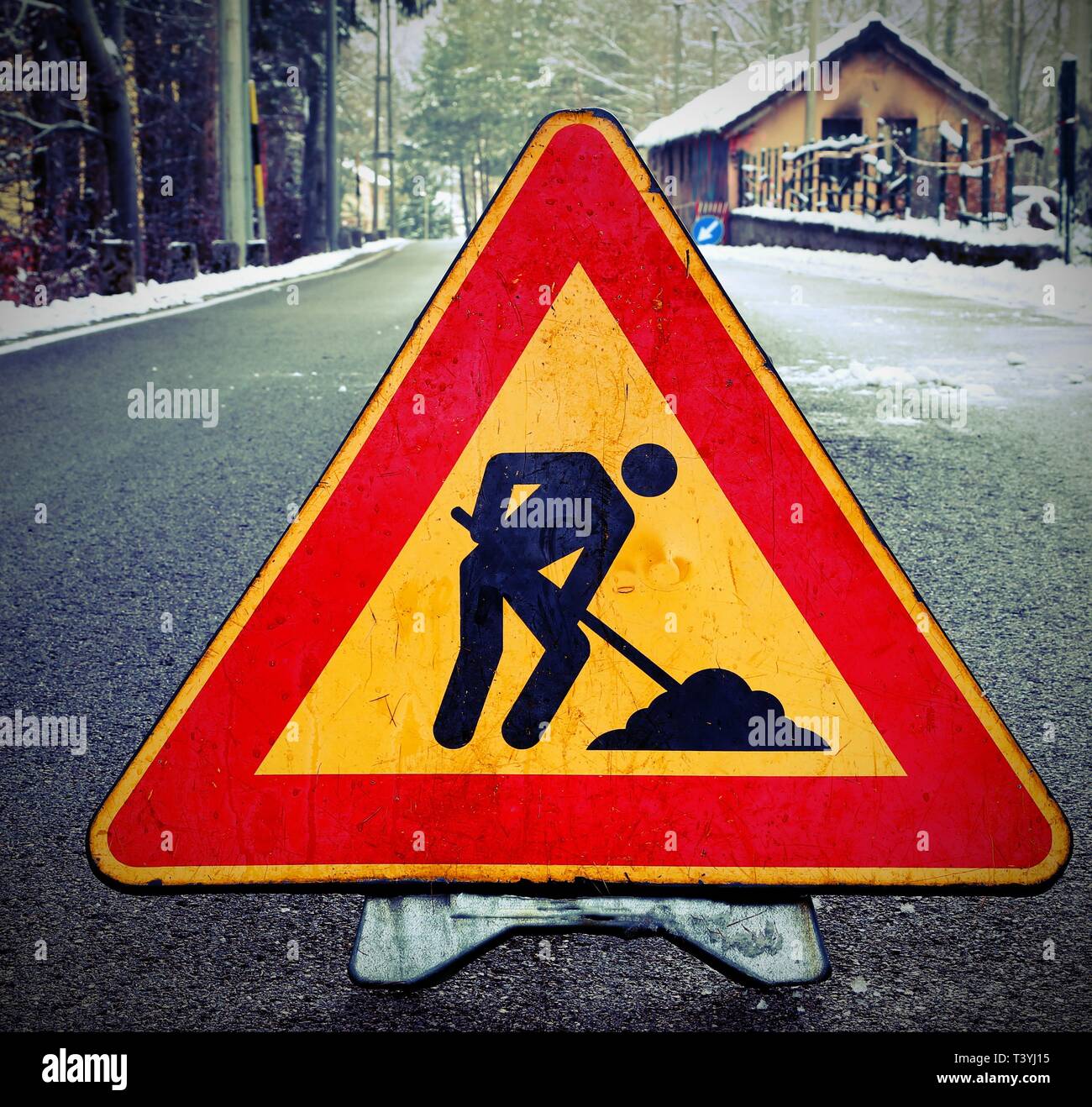 triangle sign work in progress in the road in winter with old toned ...